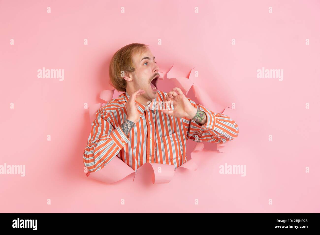Scared screaming, shouting. Cheerful caucasian young man poses in torn ...