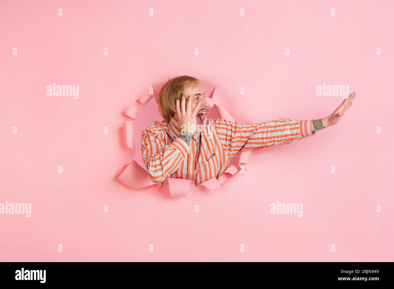 Scared screaming, shouting. Cheerful caucasian young man poses in torn ...
