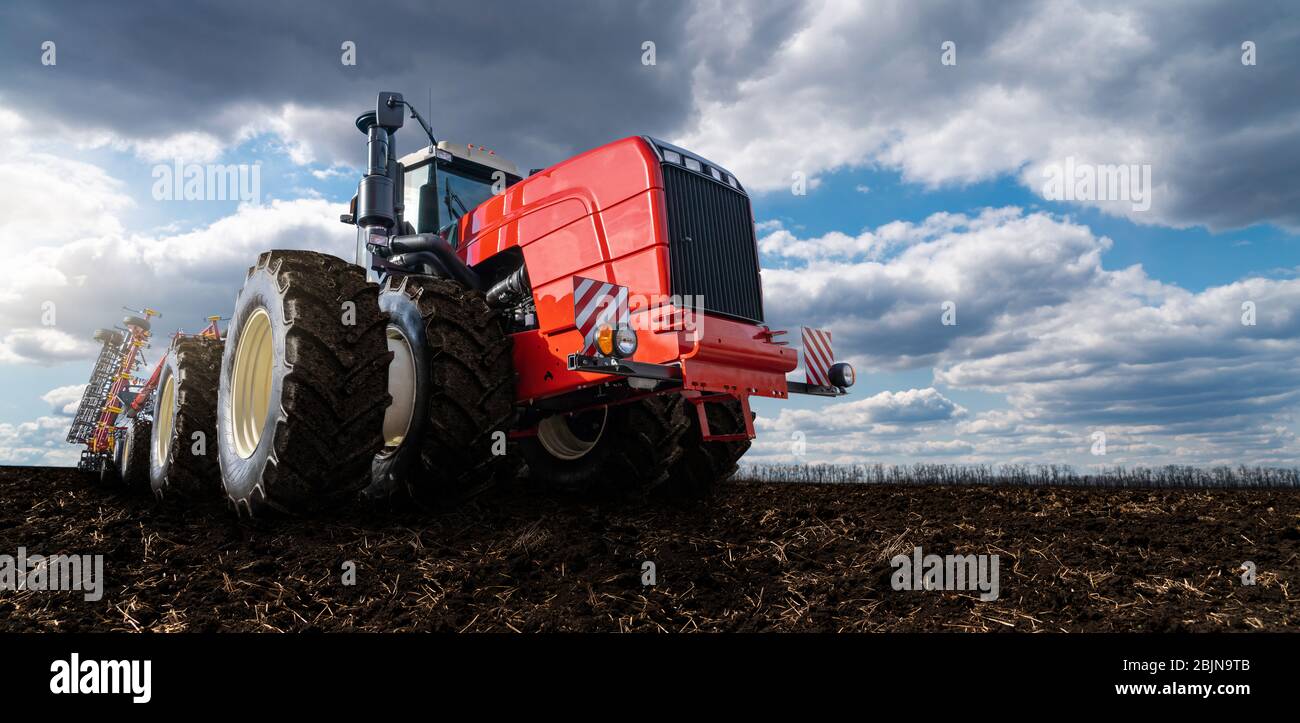 Red tractor with plow on a agricultural field Stock Photo - Alamy