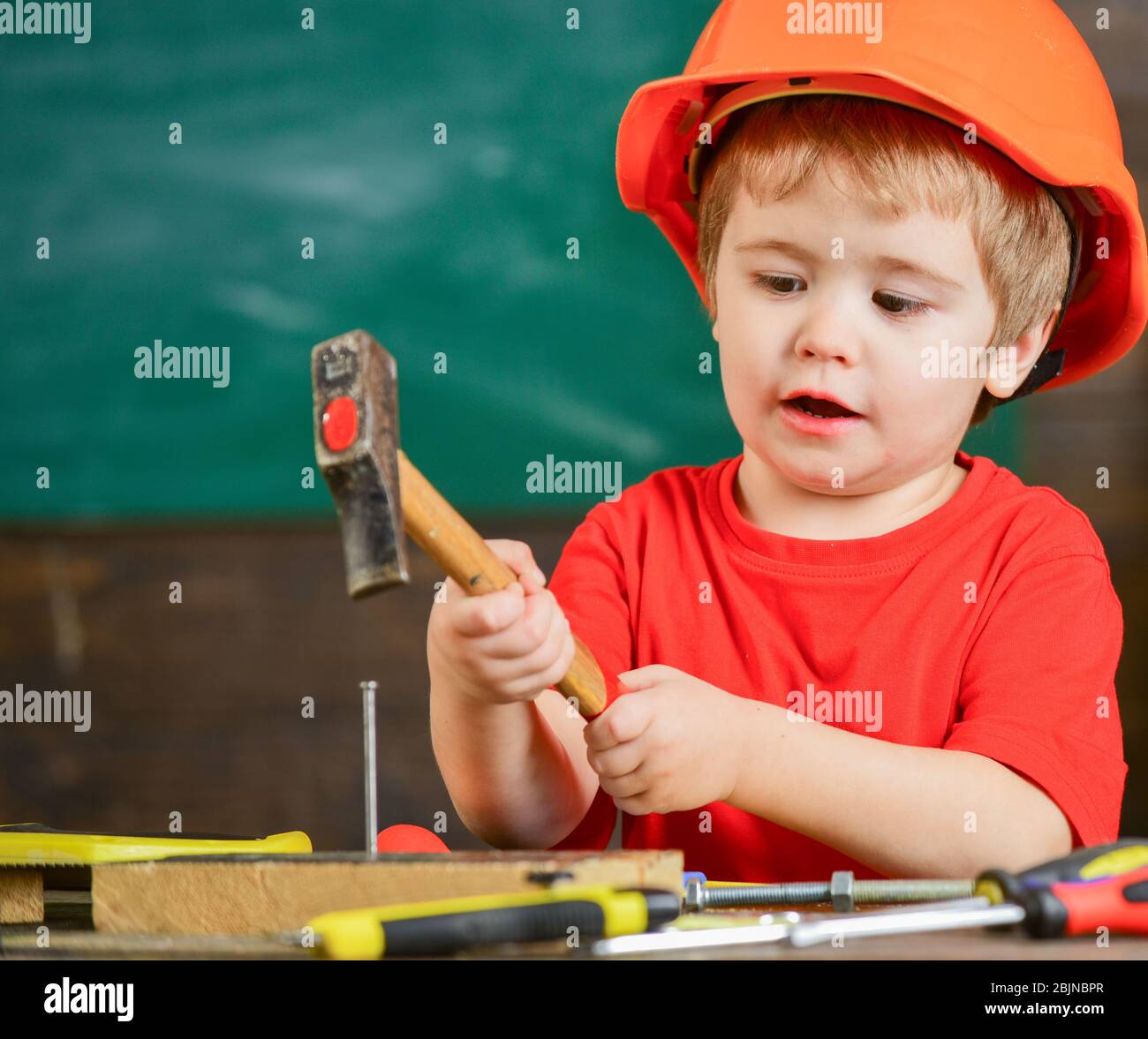 Child in helmet cute playing as builder or repairer, repairing or ...