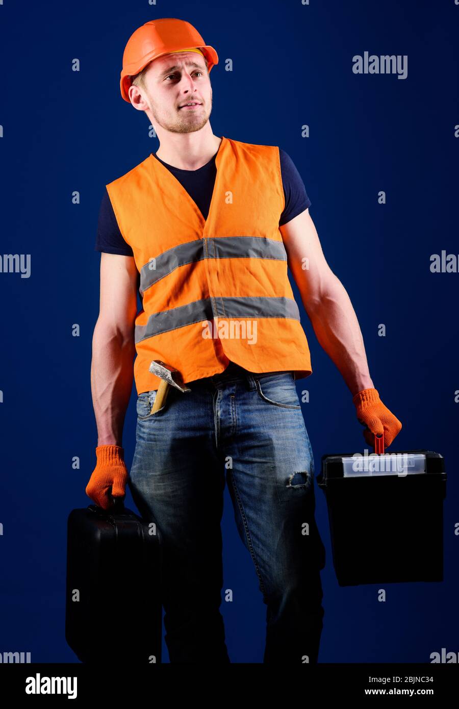 Professional repairman concept. Man in helmet, hard hat holds toolbox ...