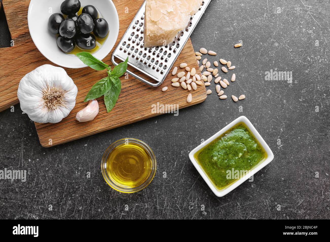 Composition with bowl of delicious basil pesto sauce on grey background ...