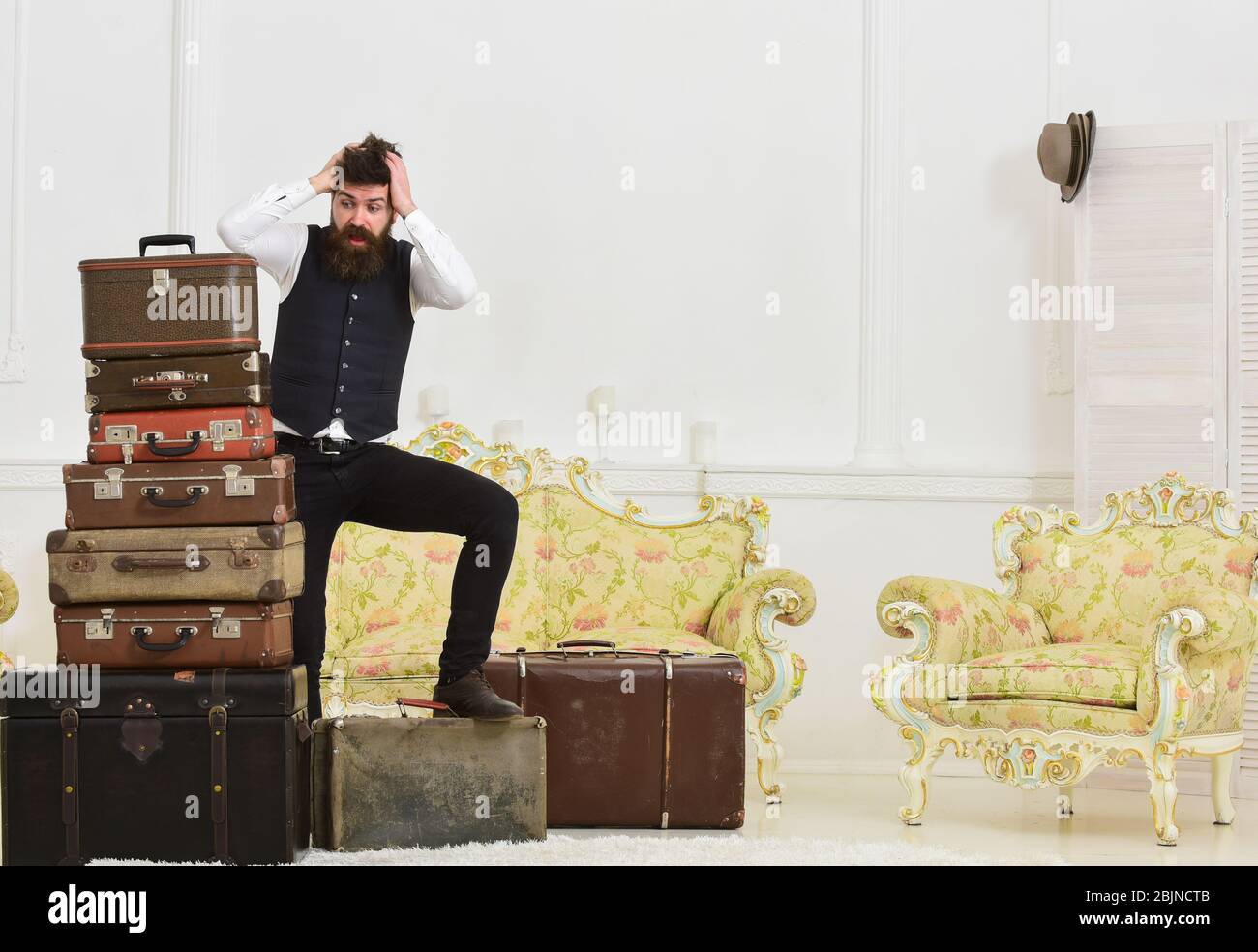 Man, butler with beard and mustache delivers luggage, luxury white ...