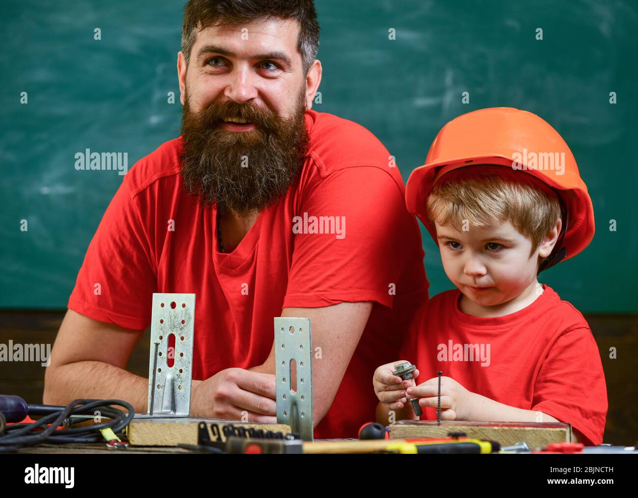 Father, parent with beard and little son in classroom, chalkboard on ...