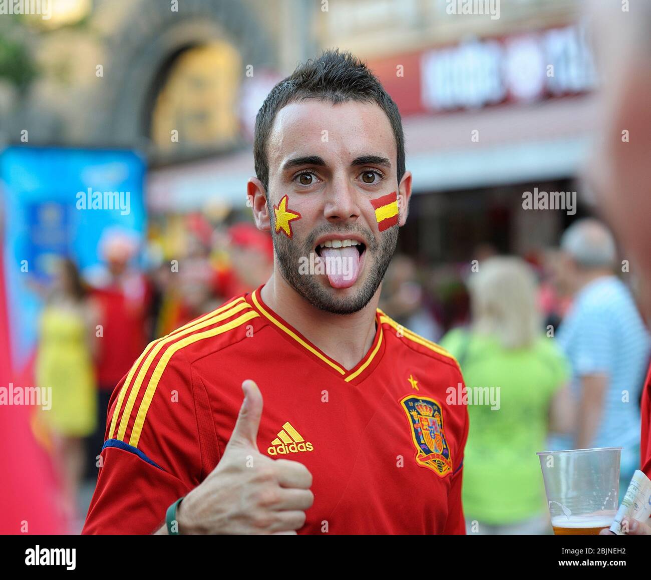 Soccer Spanish fan wearing red T-shirt, face painted in national colors ...