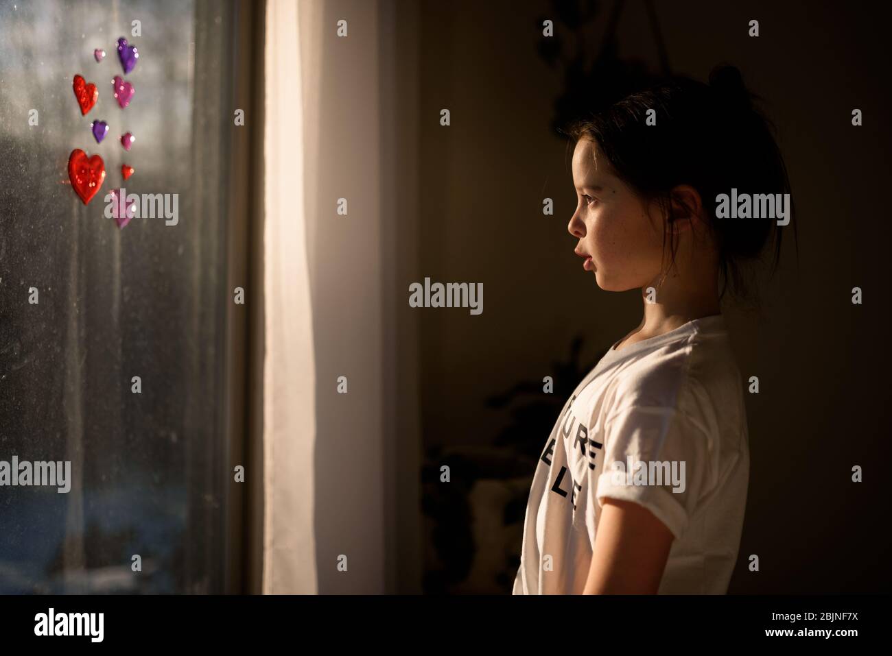 Girl looking through a window Stock Photo - Alamy