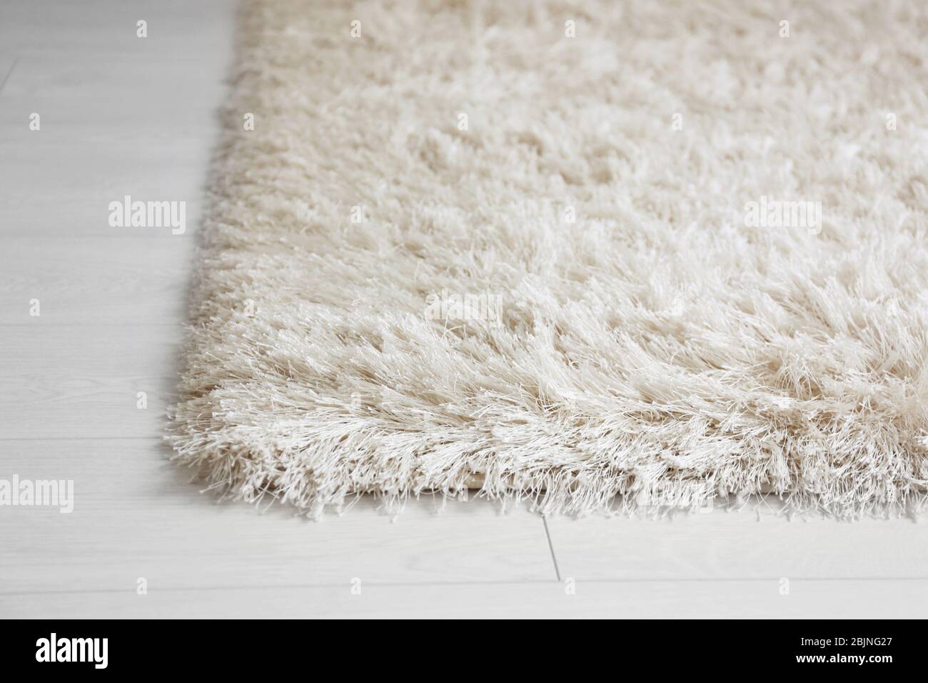 White soft carpet on wooden floor, closeup Stock Photo - Alamy
