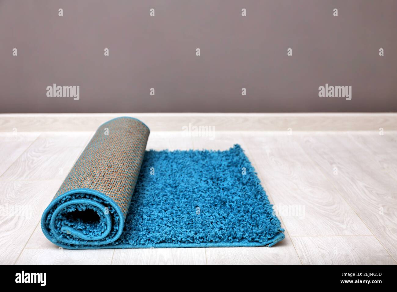 Rolled blue carpet on wooden floor Stock Photo - Alamy