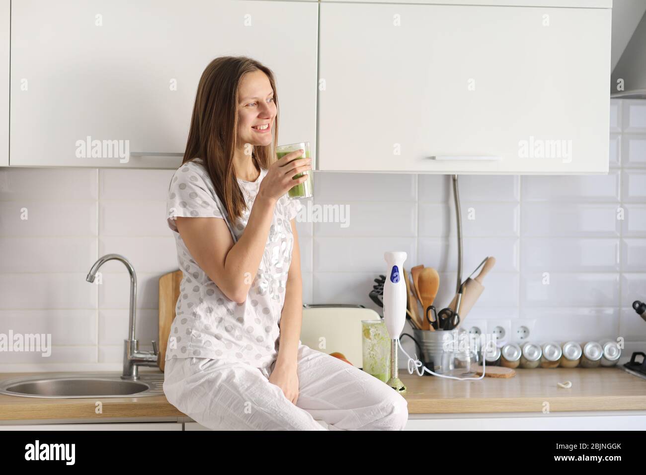 Beautiful girl drinks freshly prepared smoothie in kitchen. smoothies ...