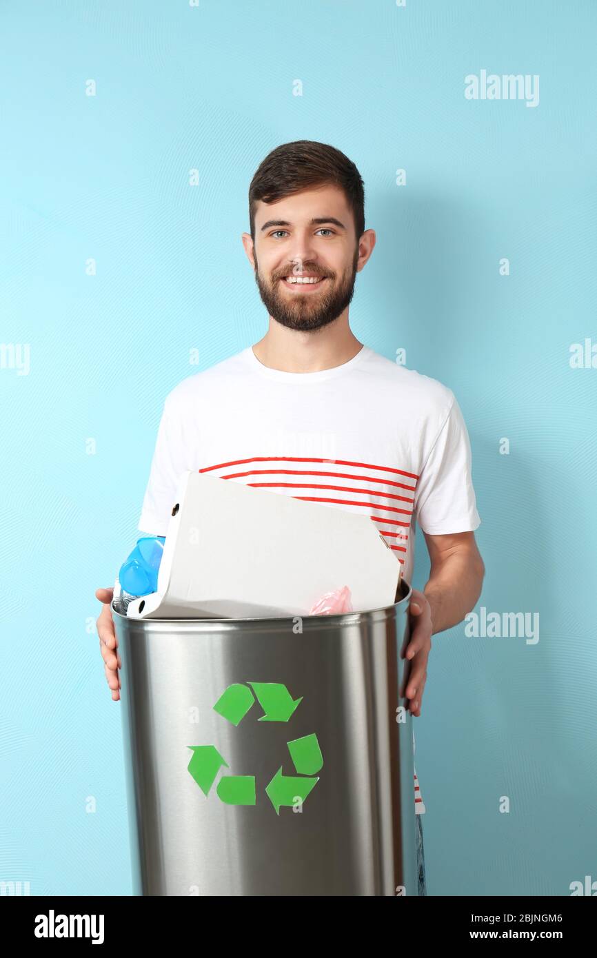 Young man with litter bin on color background. Recycling concept Stock ...