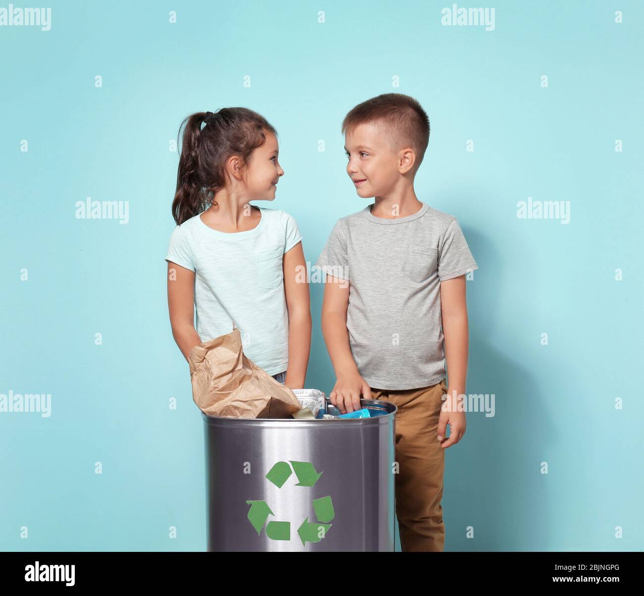 Little children with litter bin on color background. Recycling concept ...