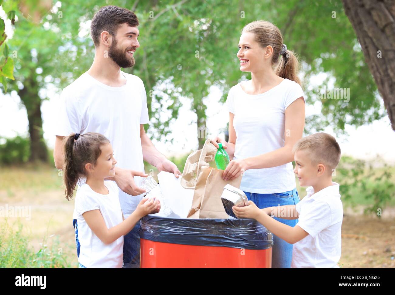 Family throwing garbage into litter bin outdoors Stock Photo - Alamy