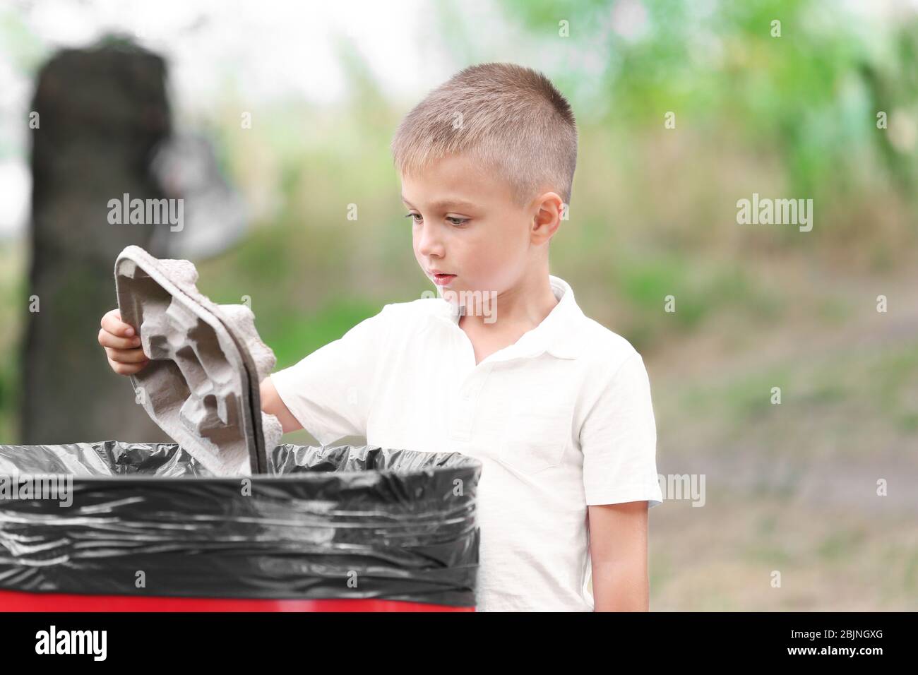 Little boy throwing garbage into litter bin outdoors Stock Photo - Alamy