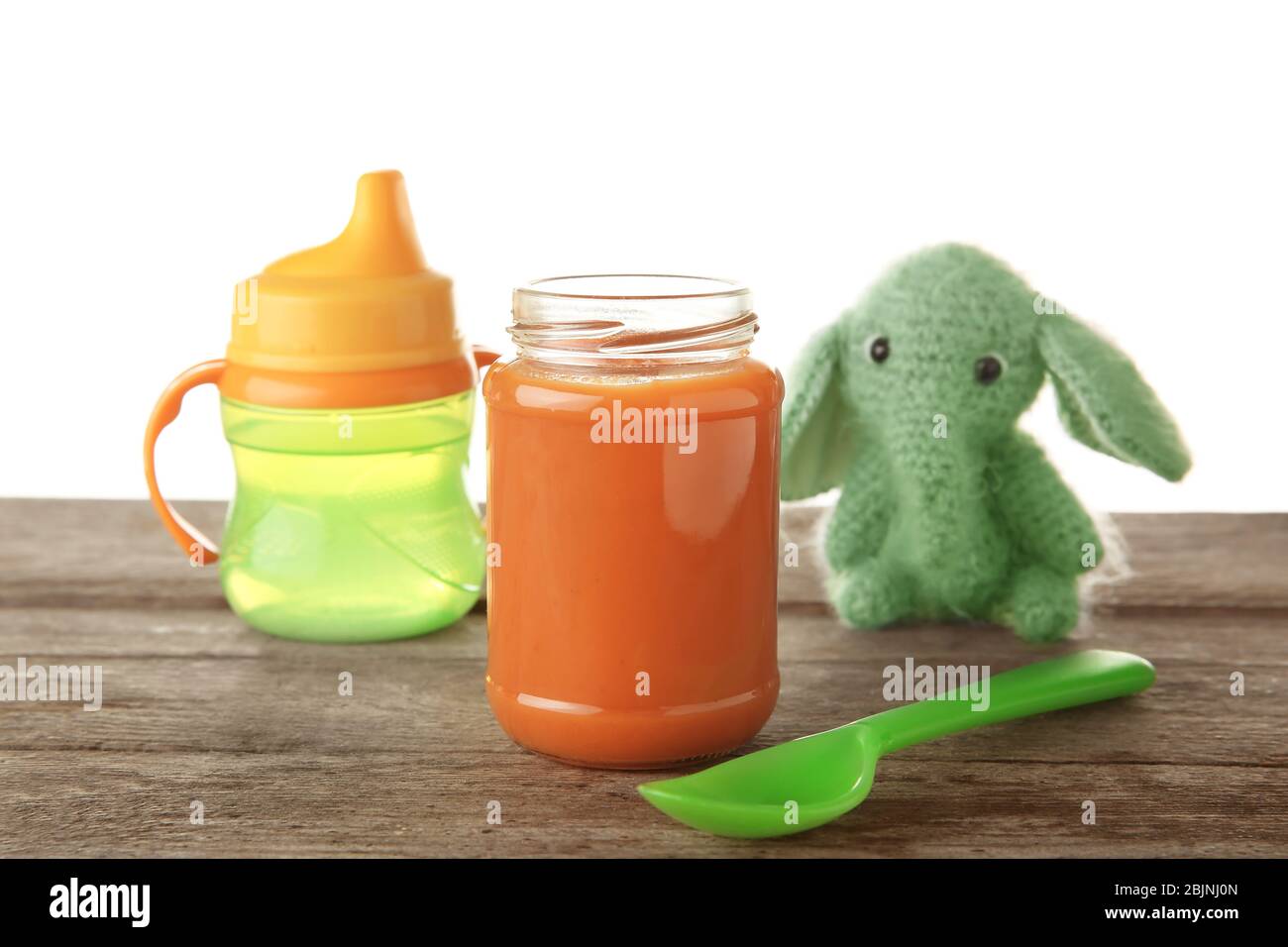 Composition with yummy baby food on wooden table against white ...