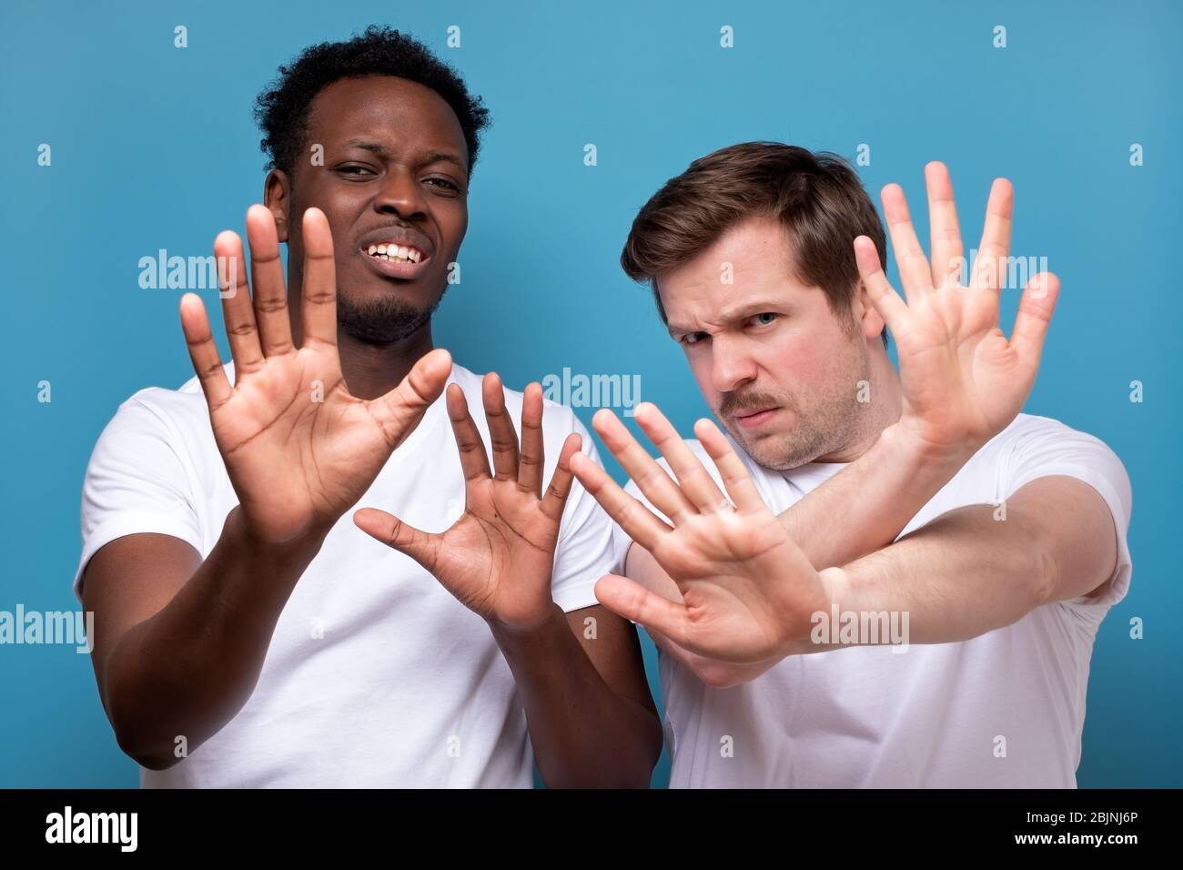 Two men african american and caucasian making stop sign making a social ...