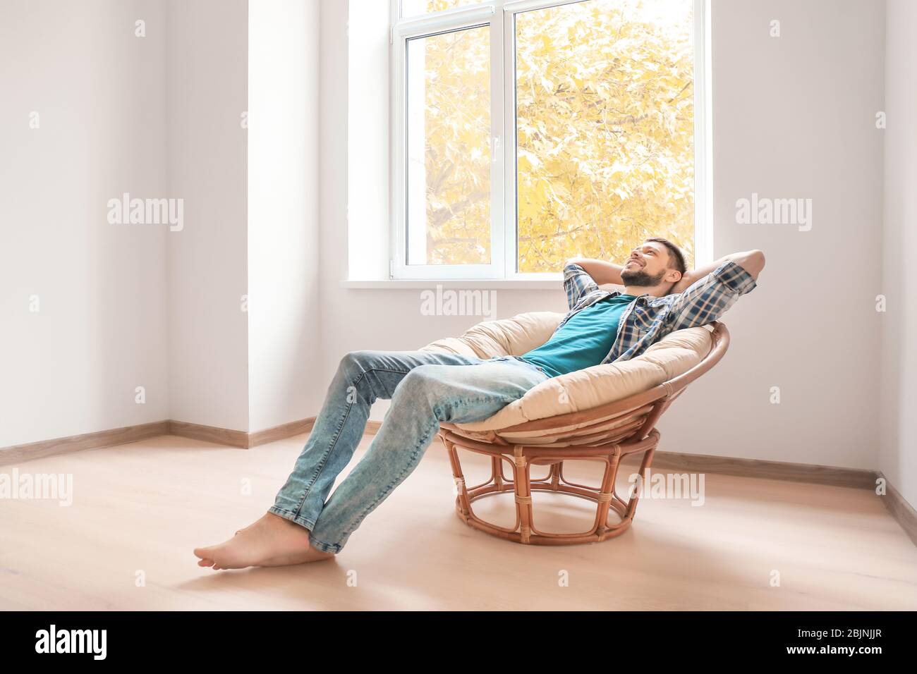 Young man resting in armchair near window at home Stock Photo - Alamy