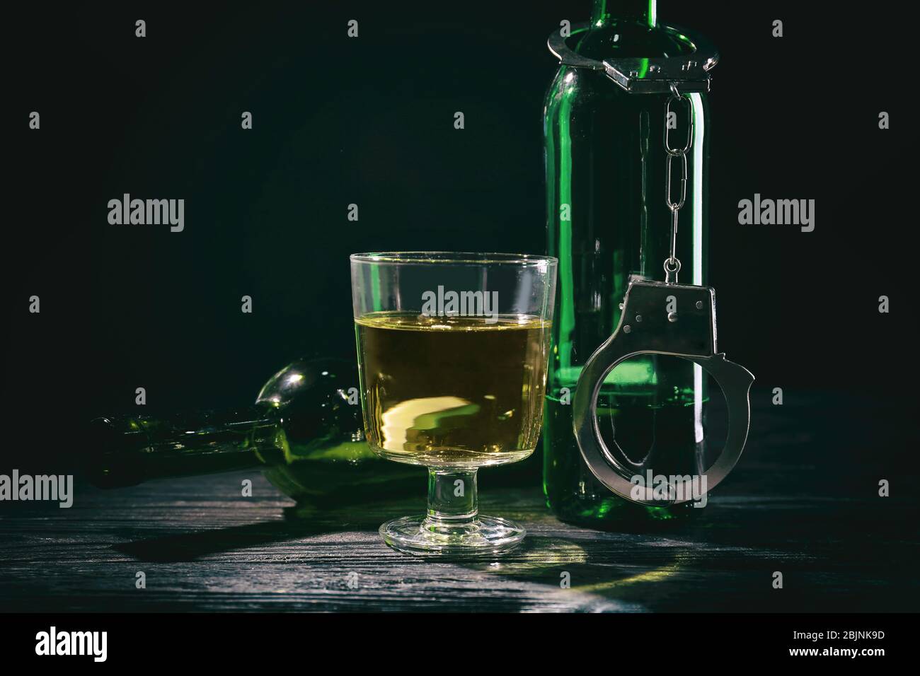 Bottles and glass of alcohol on wooden table against black background ...