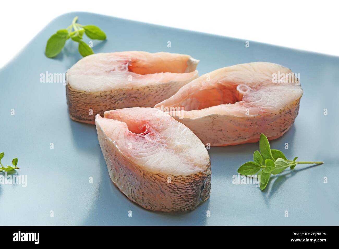 Plate with fresh fish steaks on white background Stock Photo - Alamy