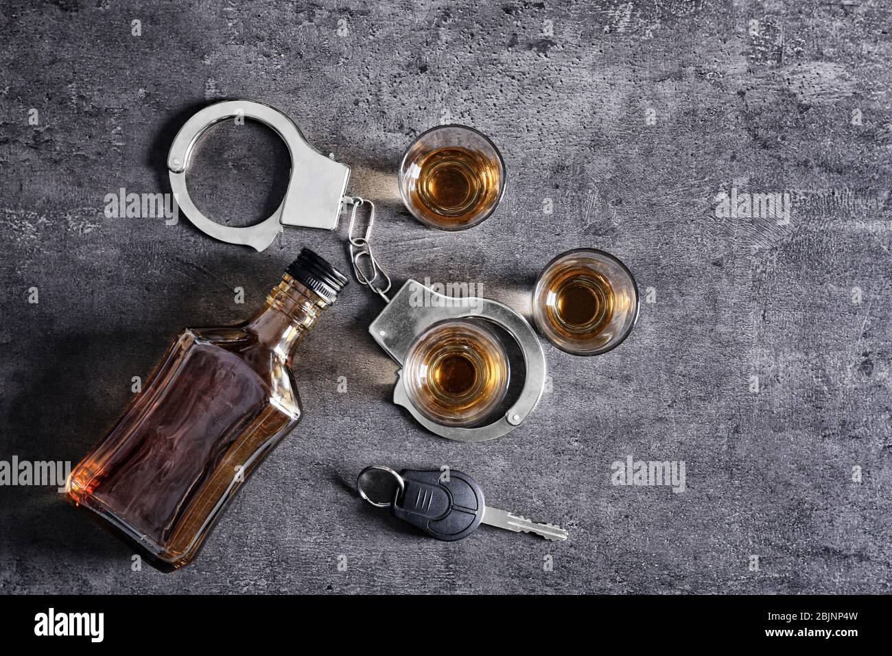 Composition with alcohol, handcuffs and car key on grey background. Don ...