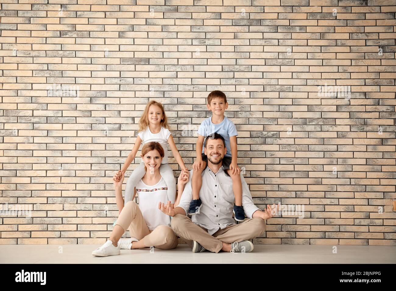 Happy family near brick wall in new empty flat Stock Photo - Alamy