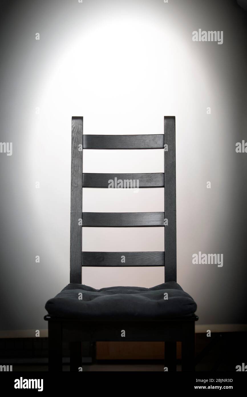 Empty black wooden chair on white background in spotlight at darkness ...