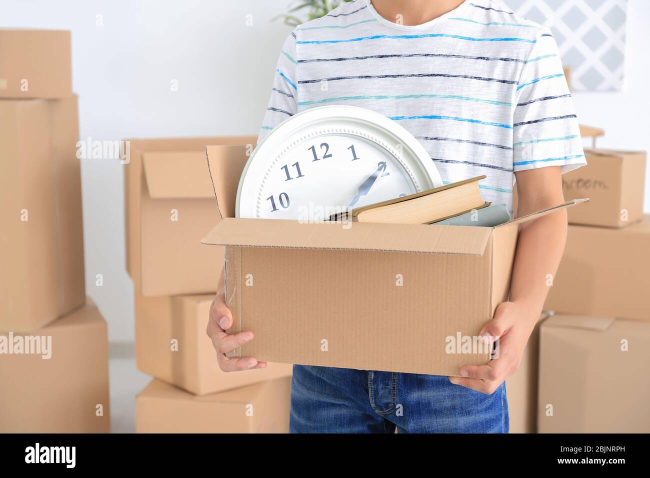 Young man holding moving box in room Stock Photo - Alamy