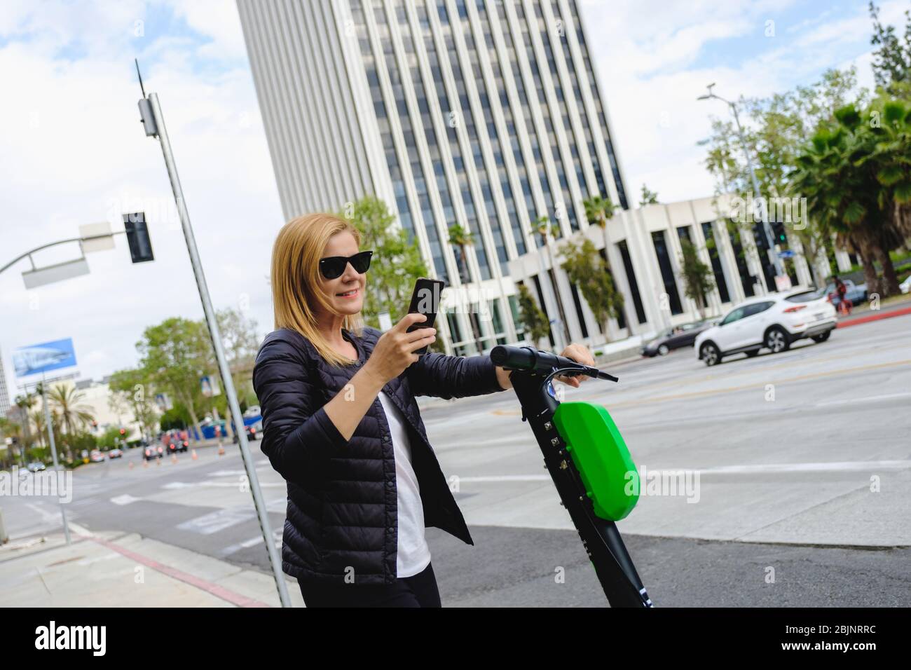 Beautiful stylish woman scanning the qr code with her phone to rent an ...