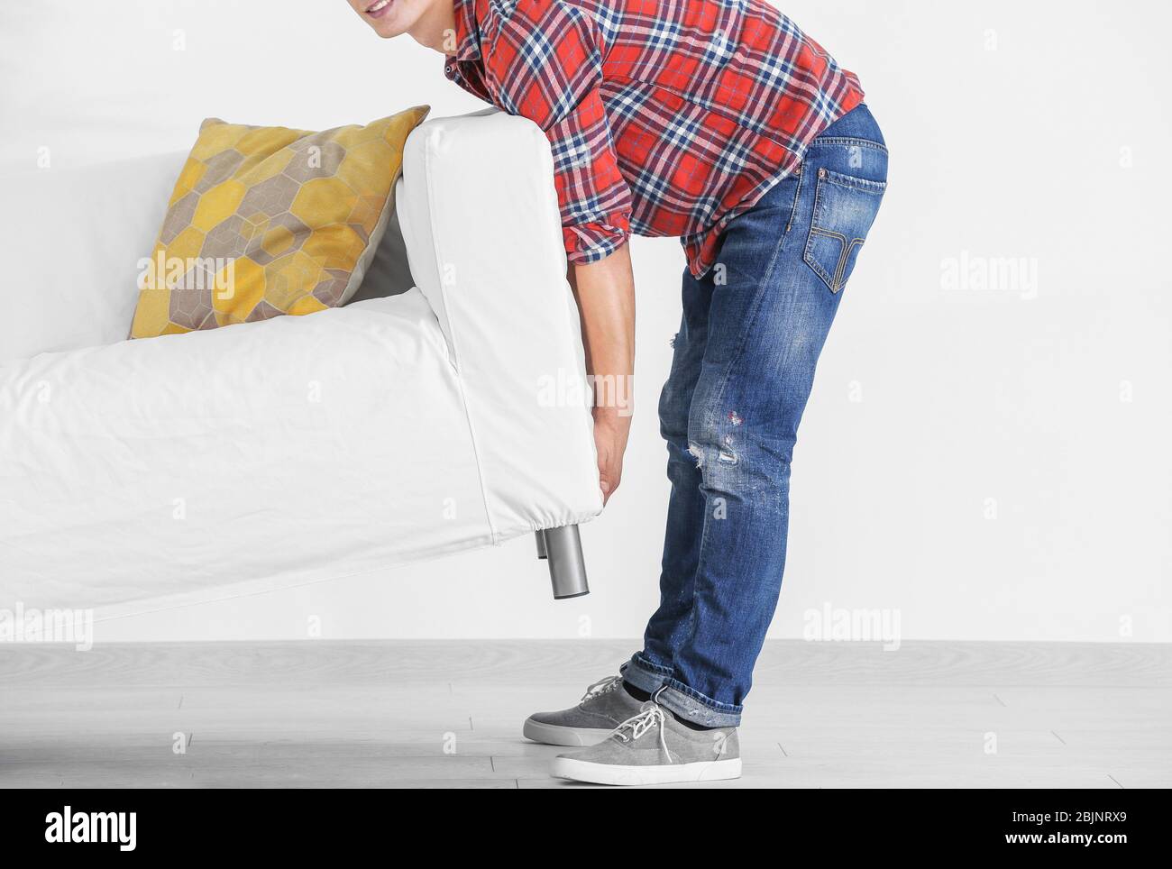 Young man moving sofa in room at new home Stock Photo - Alamy