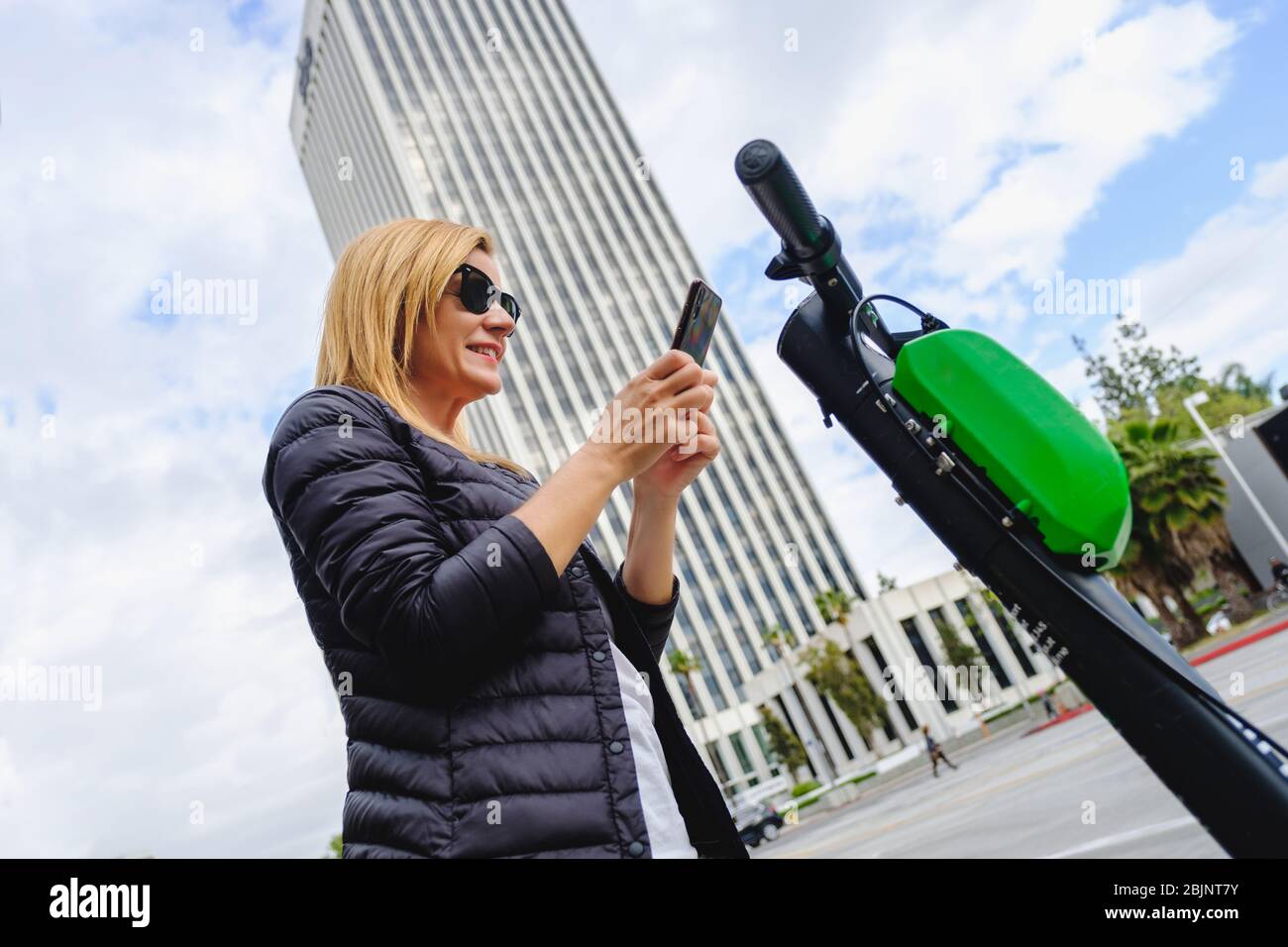 Beautiful stylish woman scanning the qr code with her phone to rent an ...