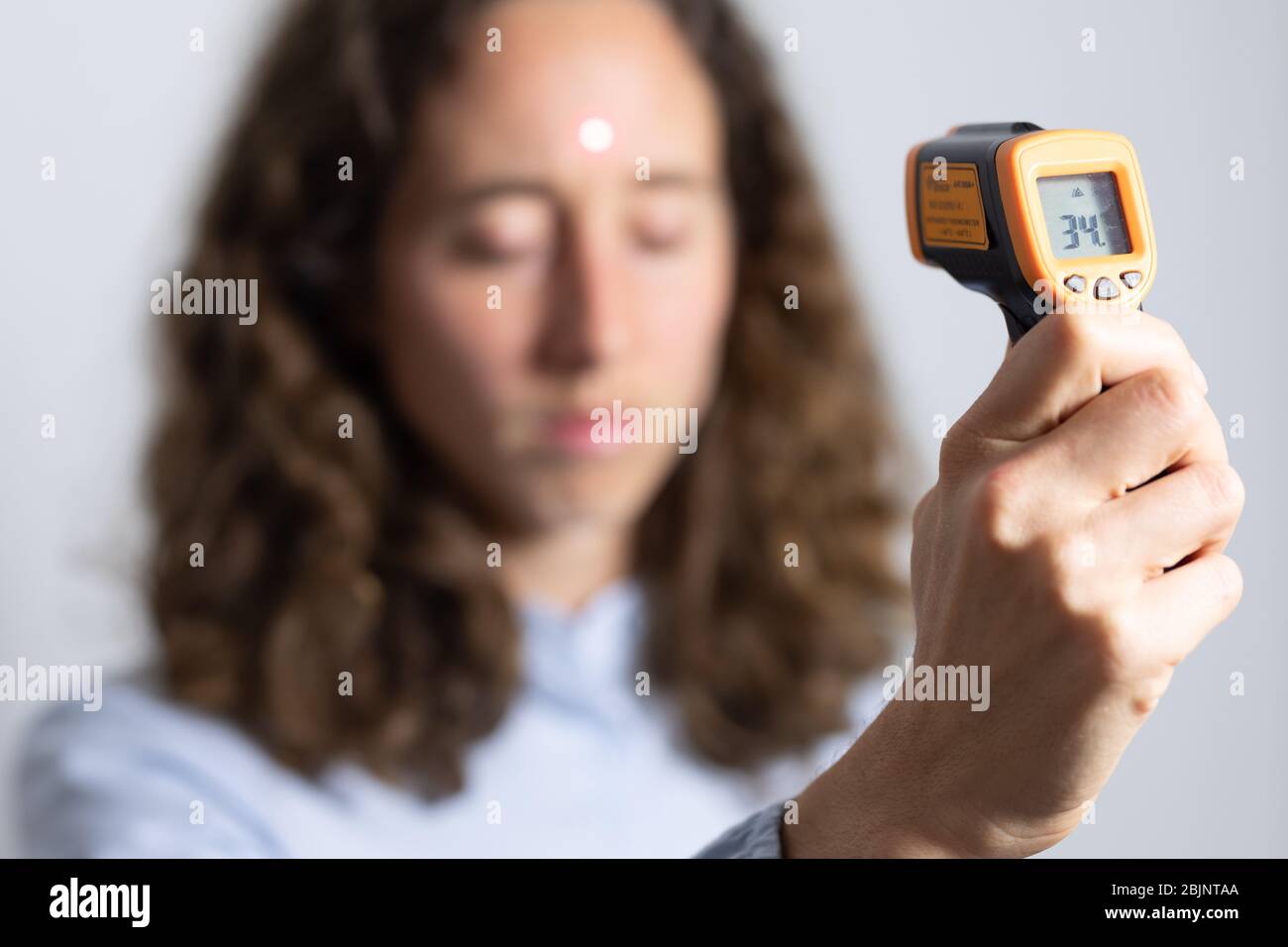 Caucasian woman with long curly hair, examining her temperature ...