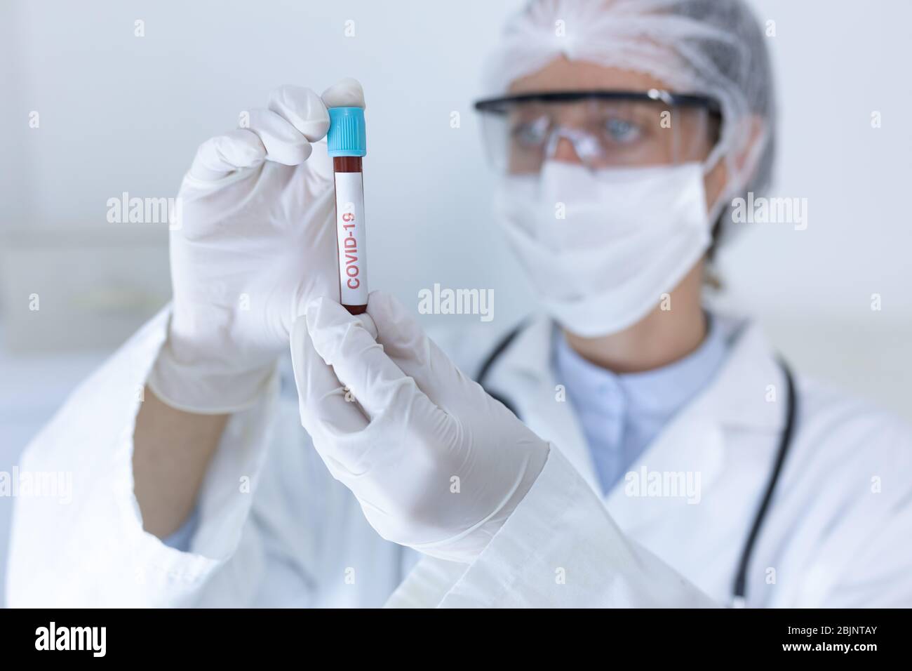 Caucasian female healthcare worker wearing a lab coat, face mask and ...