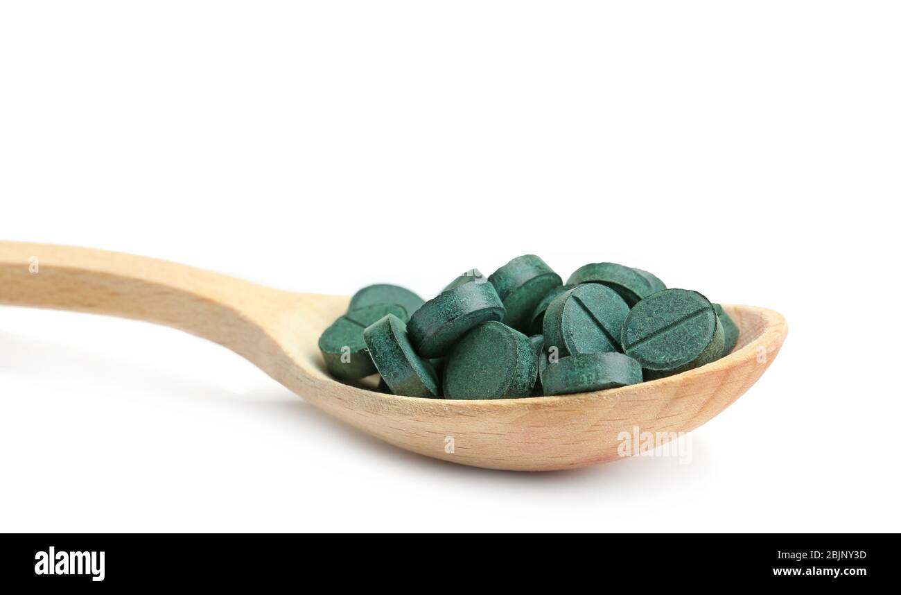 Spoon with spirulina tablets on white background Stock Photo - Alamy