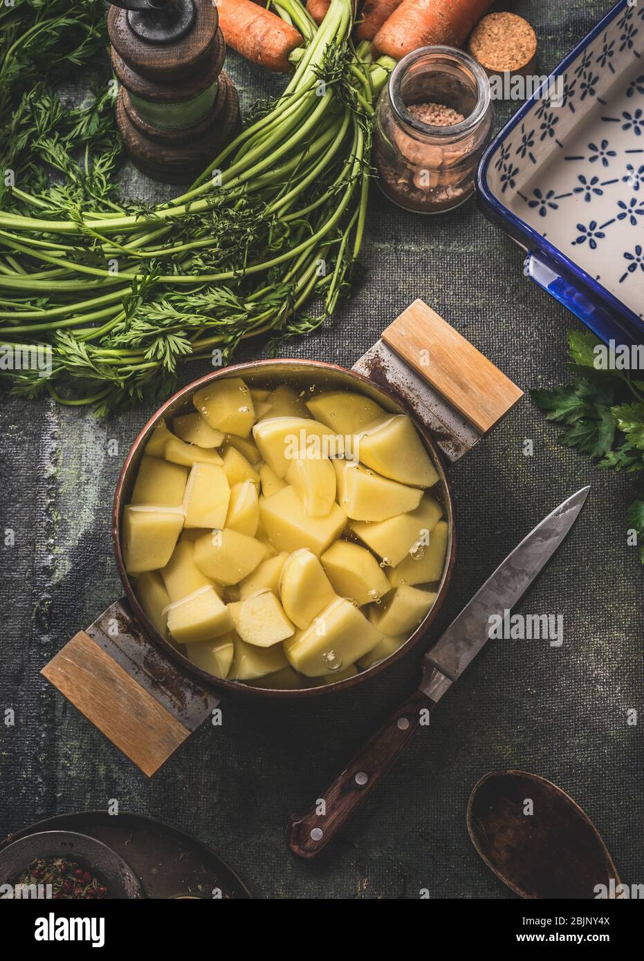 Raw potatoes in copper cooking pot in water on rustic kitchen table ...
