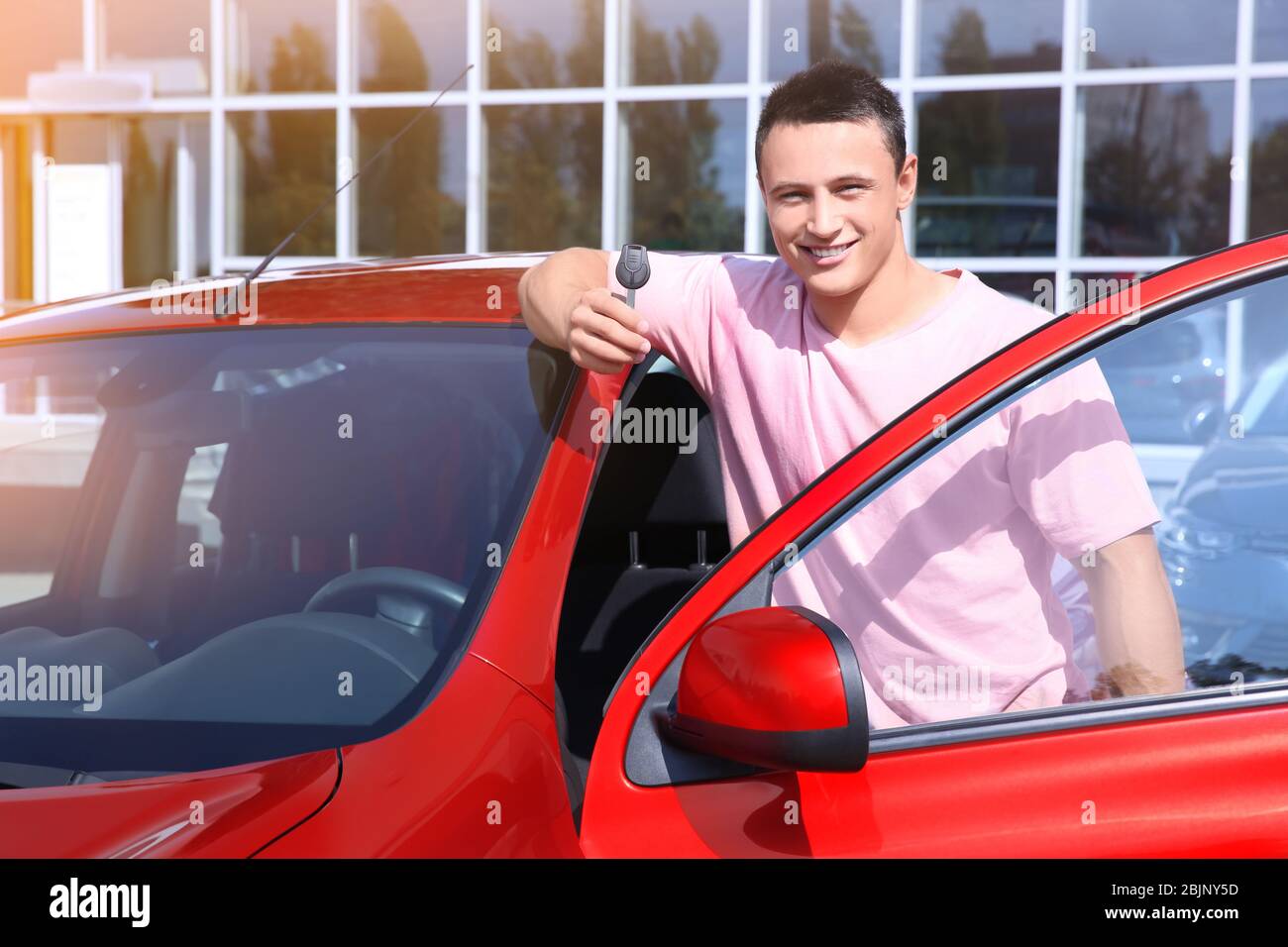 Happy young man with key from new car outdoors Stock Photo - Alamy