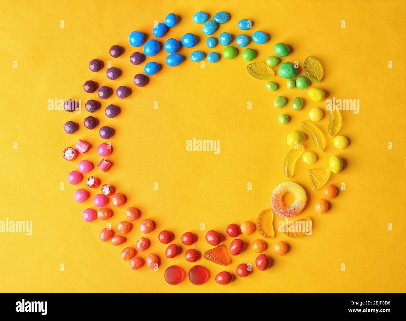 Colorful candies arranged as circle on yellow background Stock Photo ...