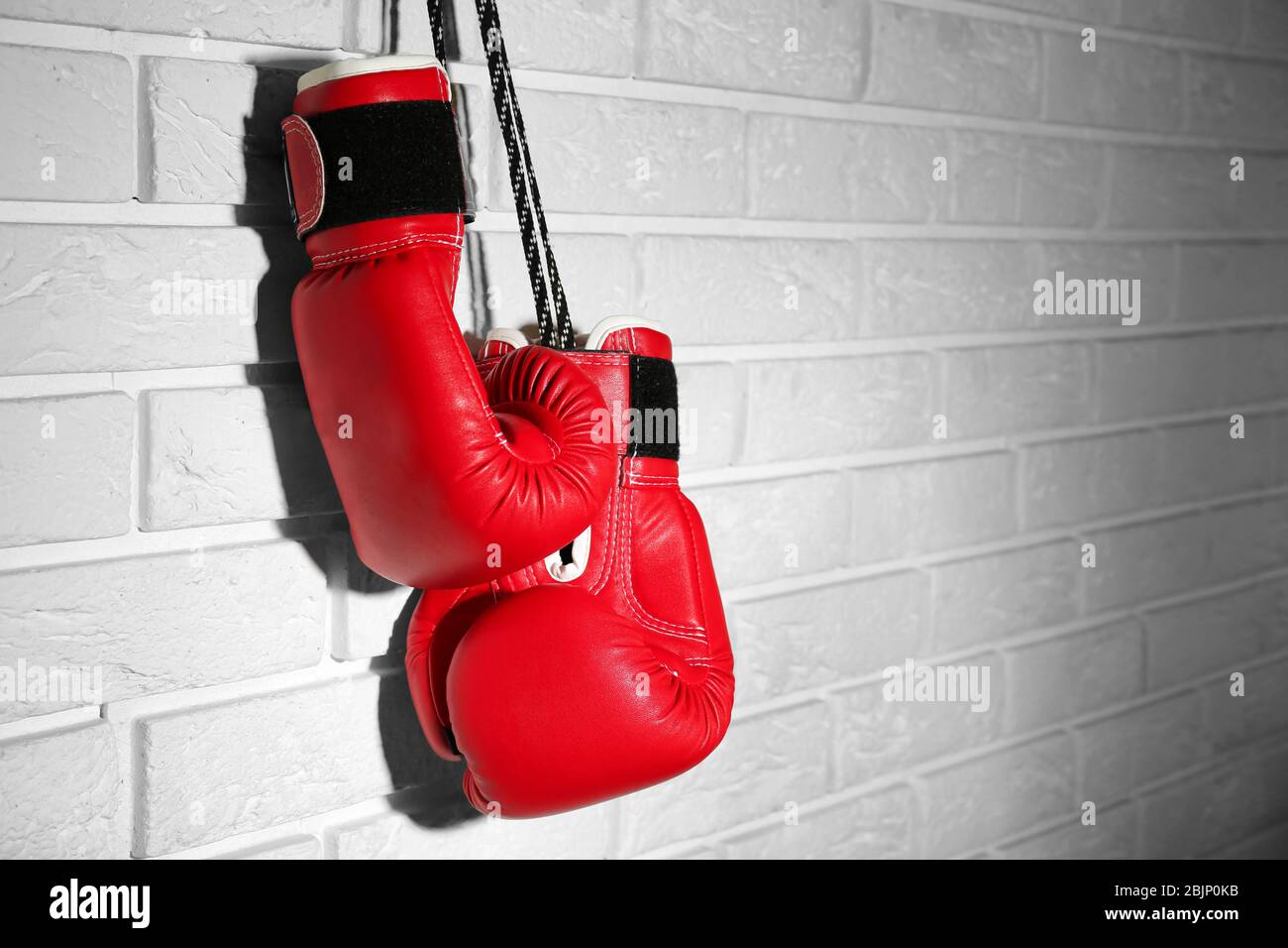 Pair of red boxing gloves hanging on brick wall Stock Photo - Alamy