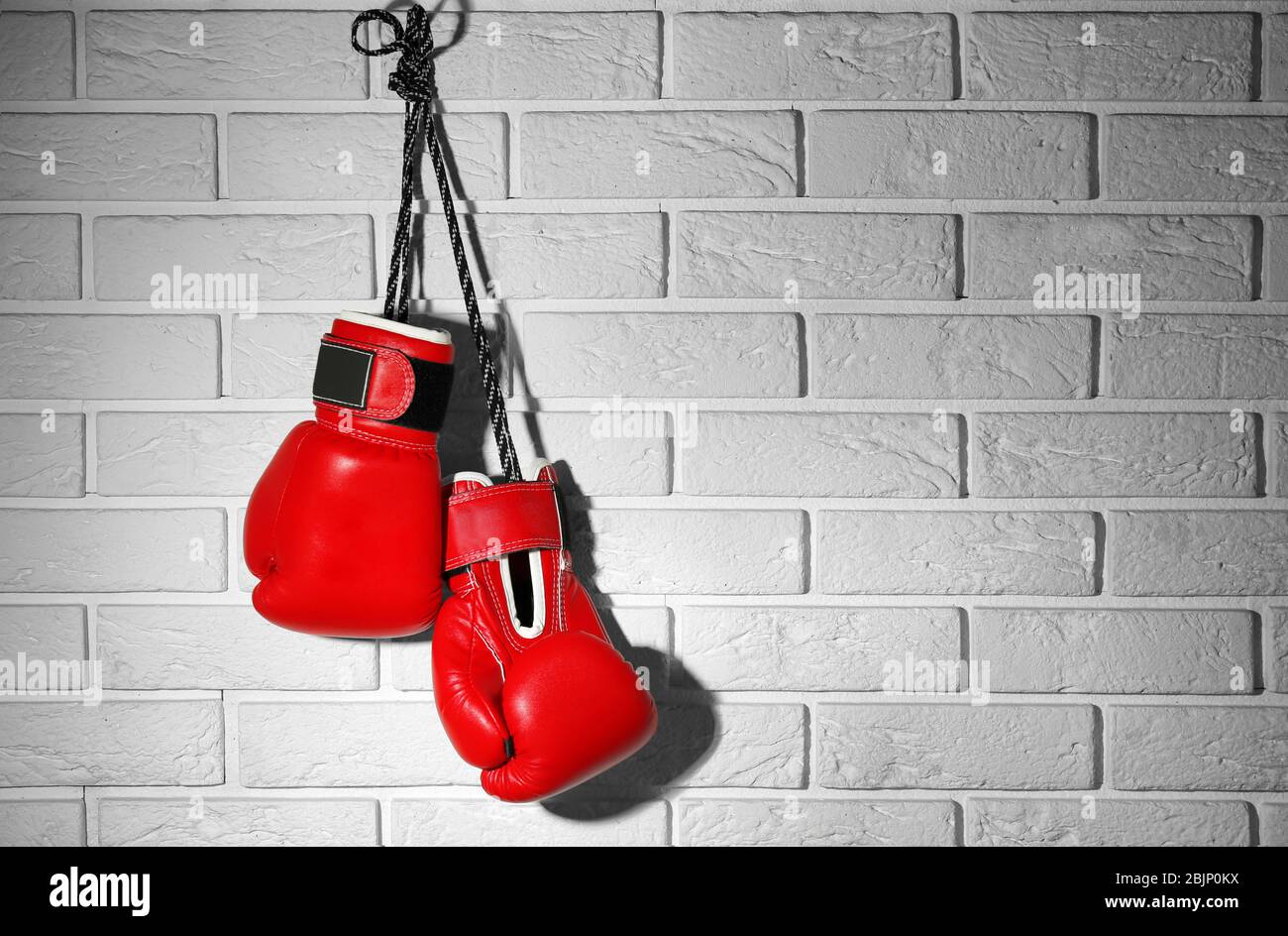 Pair of red boxing gloves hanging on brick wall Stock Photo - Alamy
