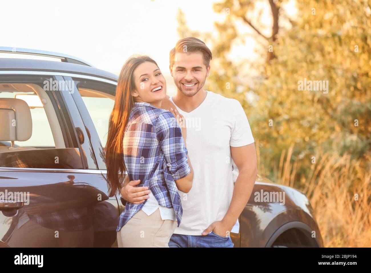 Beautiful young couple standing near car Stock Photo - Alamy