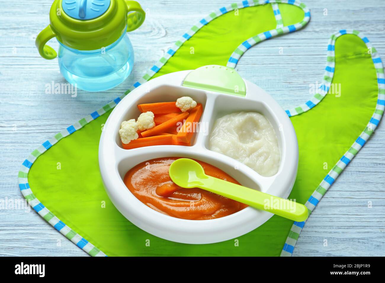 Section plate with baby food on wooden background Stock Photo - Alamy