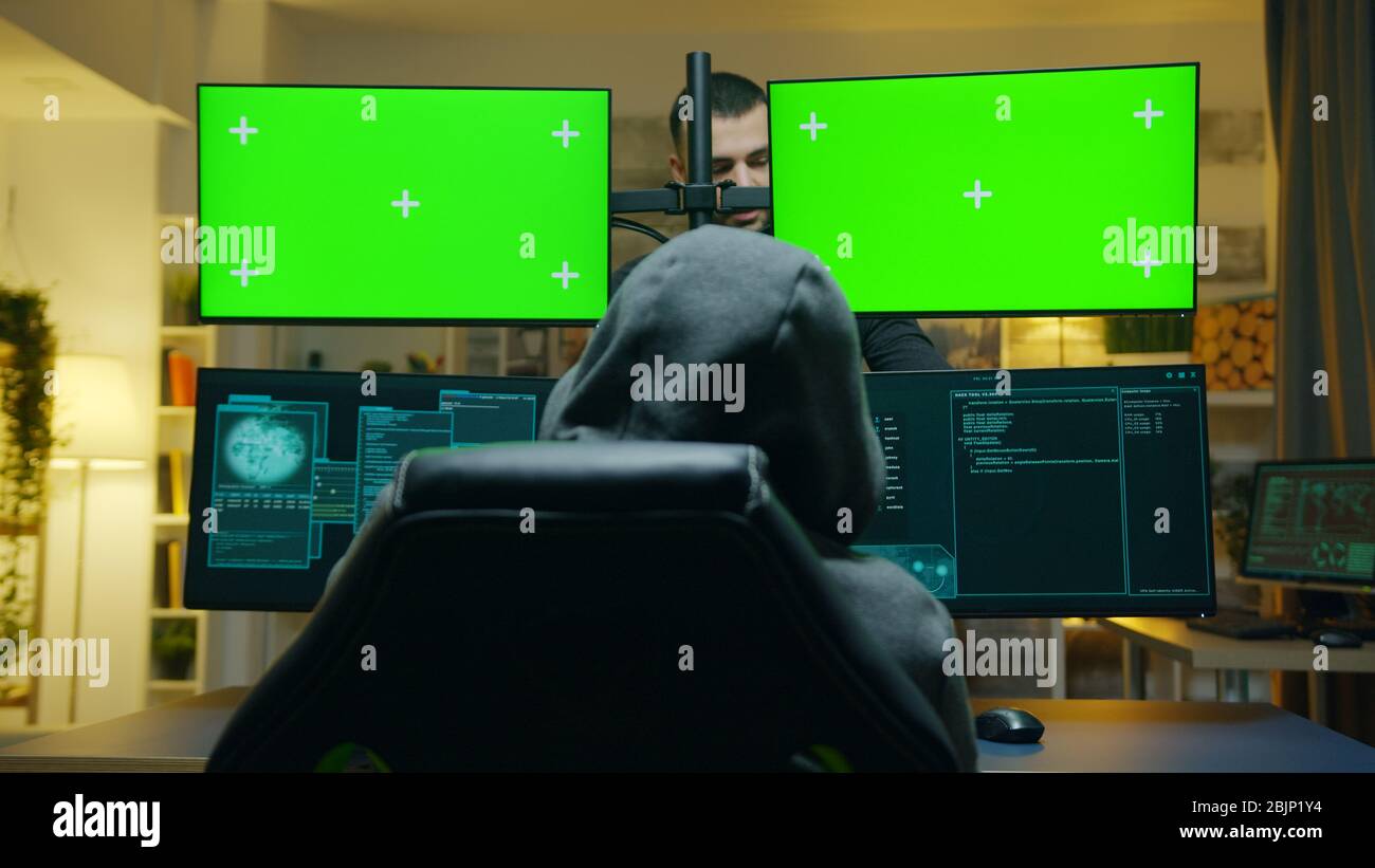 Team of hackers using computer with green screen mockup to steal secret ...