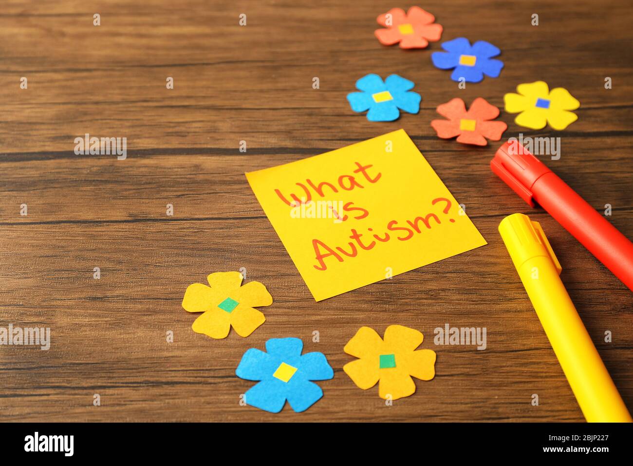 Paper flowers, markers and sticky note with words What is autism on ...