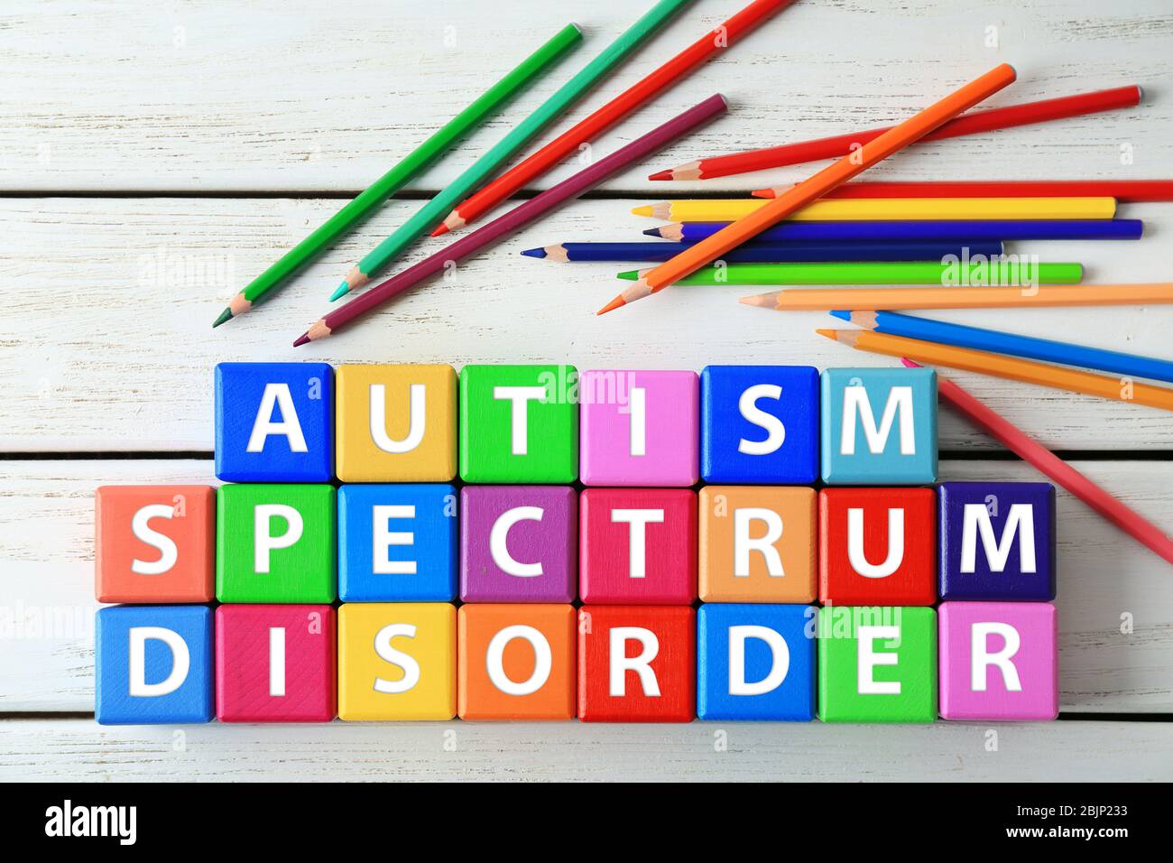 Colorful cubes and pencils on wooden background. Autism awareness ...