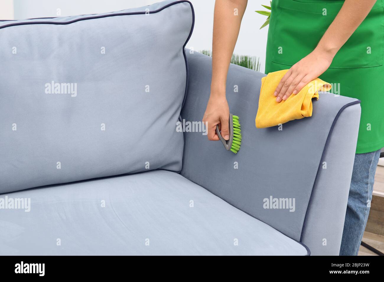 Woman cleaning couch with brush and duster at home Stock Photo - Alamy