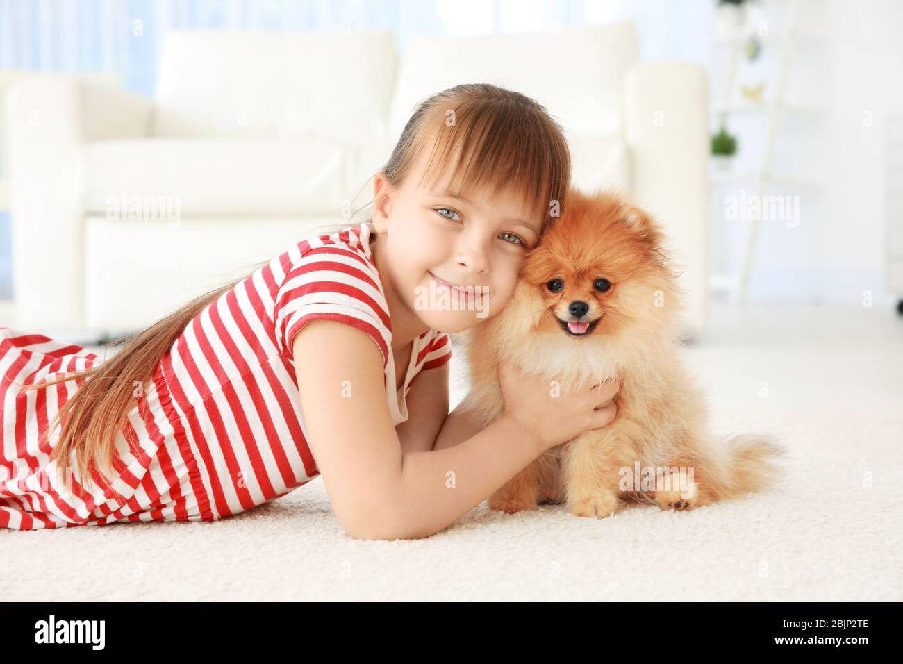 Cute girl with little dog on floor at home Stock Photo - Alamy