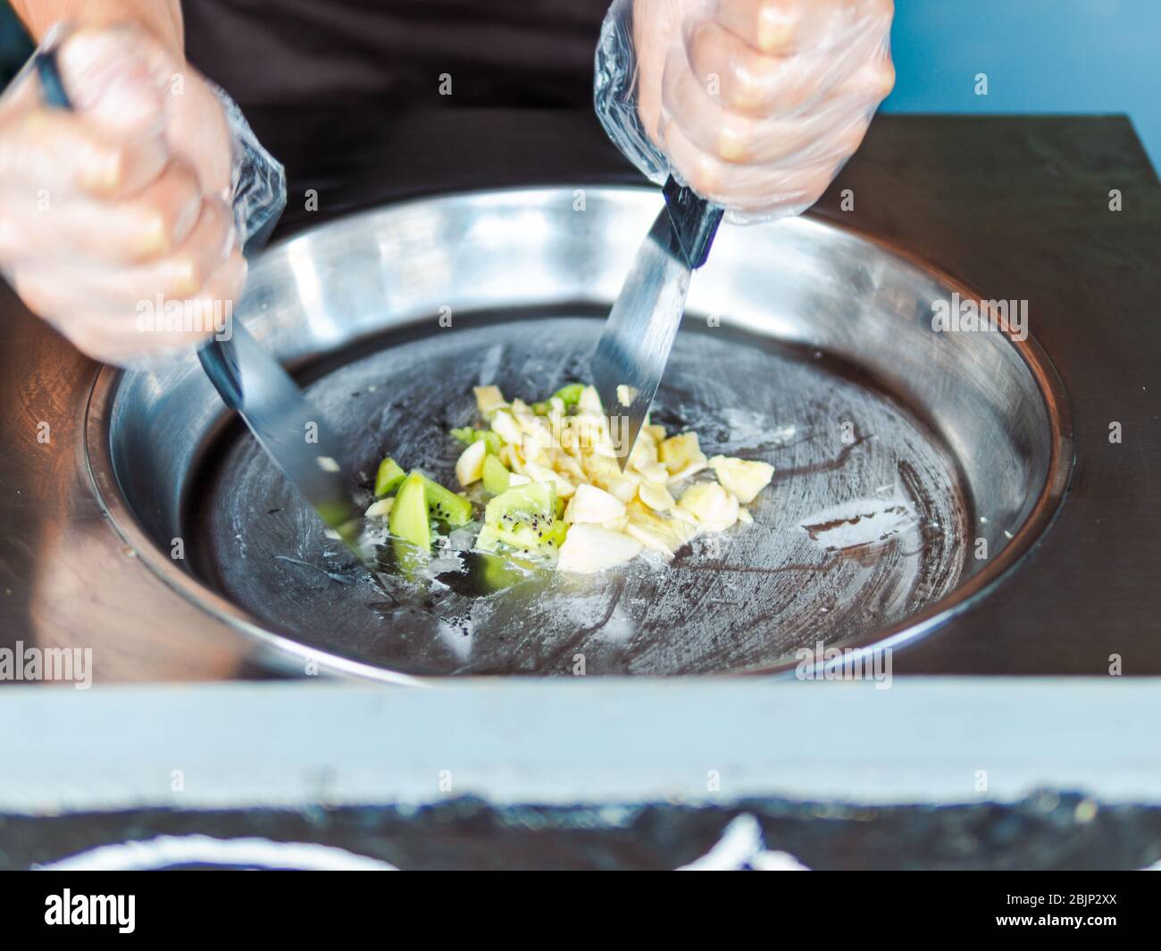 Making rolled ice cream. Man hands making kiwi and banana Thay style ...