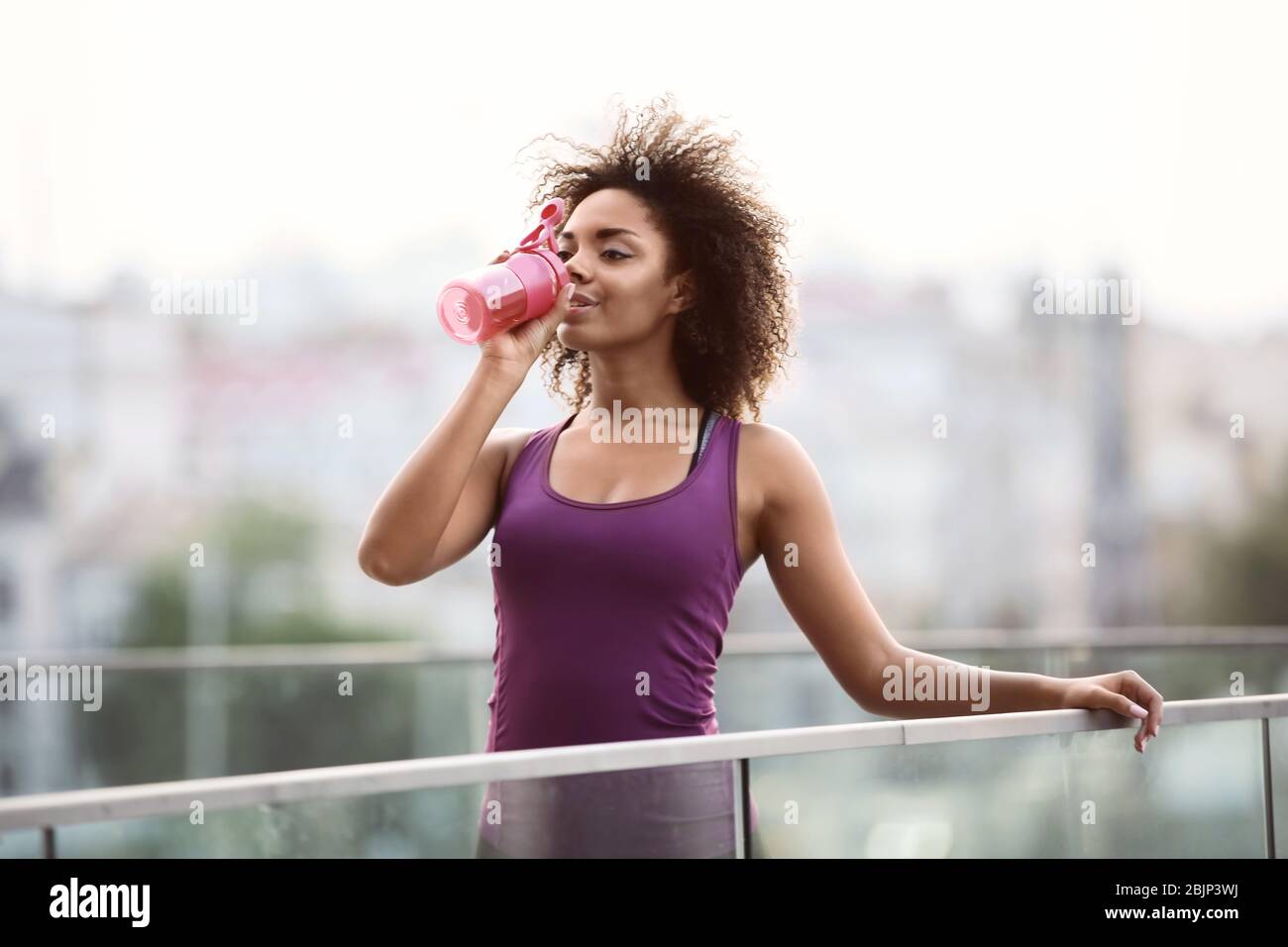 Sporty African American woman drinking water outdoors Stock Photo - Alamy