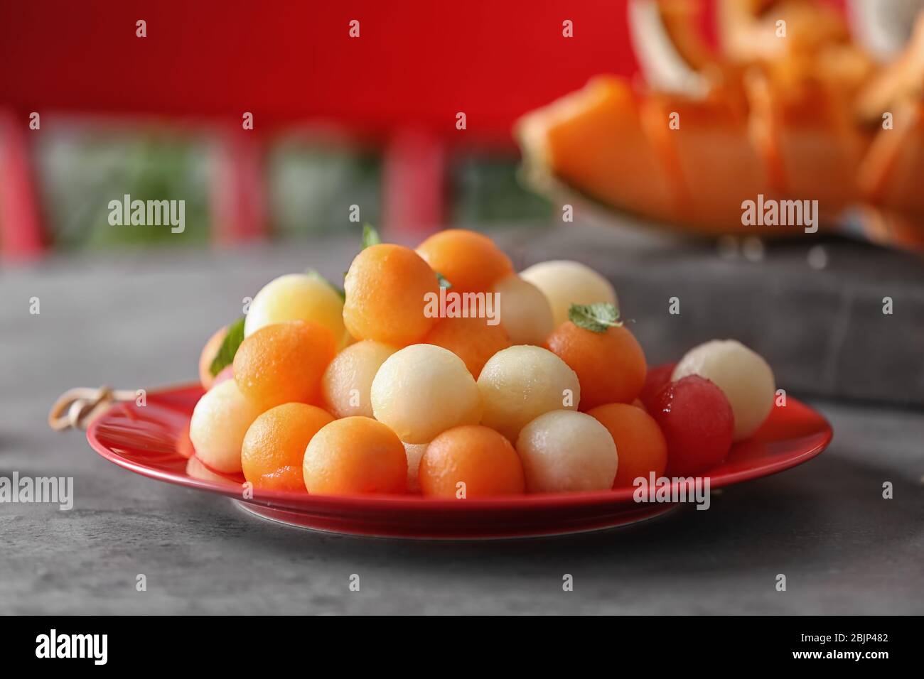 Plate with fresh fruit balls on table Stock Photo - Alamy