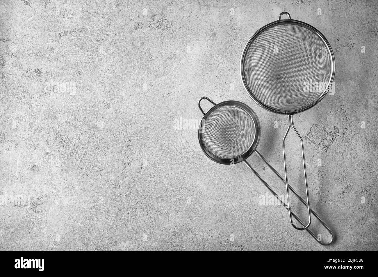 Two sieves on light textured background Stock Photo - Alamy