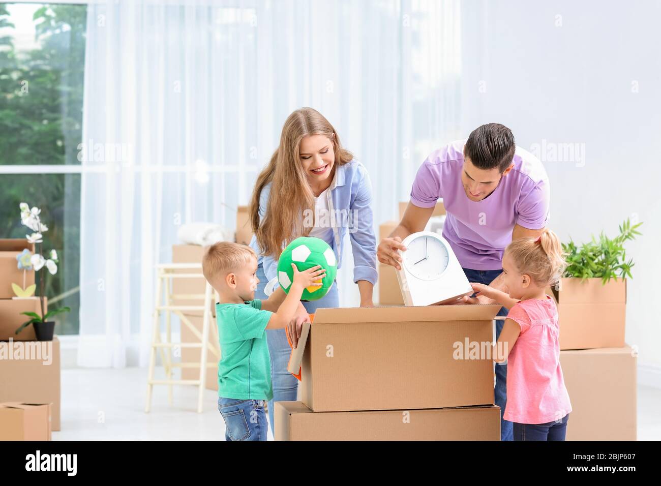 Happy family unpacking moving boxes in their new house Stock Photo - Alamy