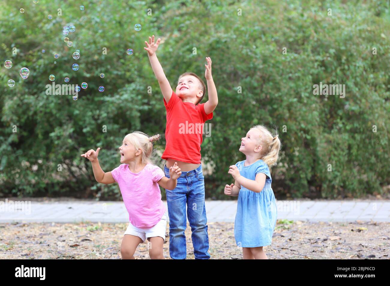 Adorable little children catching soap bubbles outdoors Stock Photo - Alamy